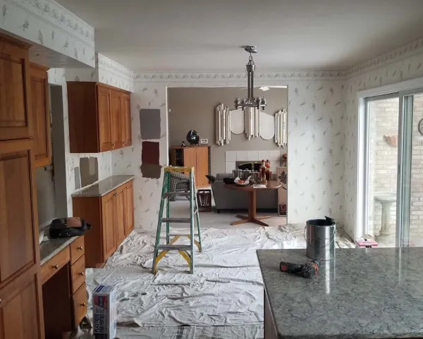 Kitchen renovation in progress with paint samples on walls and a ladder ...